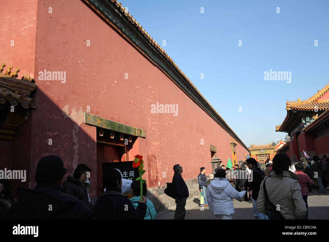 iconic red wall of The Forbidden City with tour groups in shadows ...