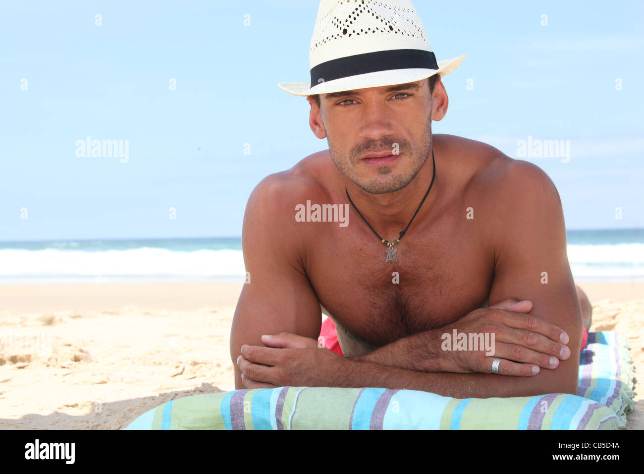 Man wearing hat sunbathing at beach Stock Photo - Alamy