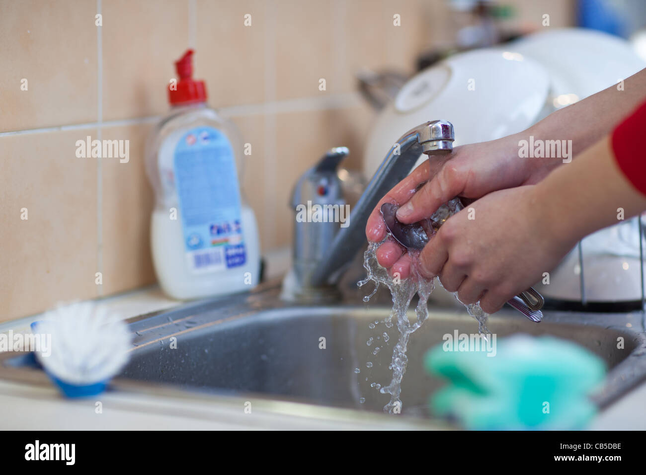 Washing of the dishes - woman hands rinsing dishes under running water ...