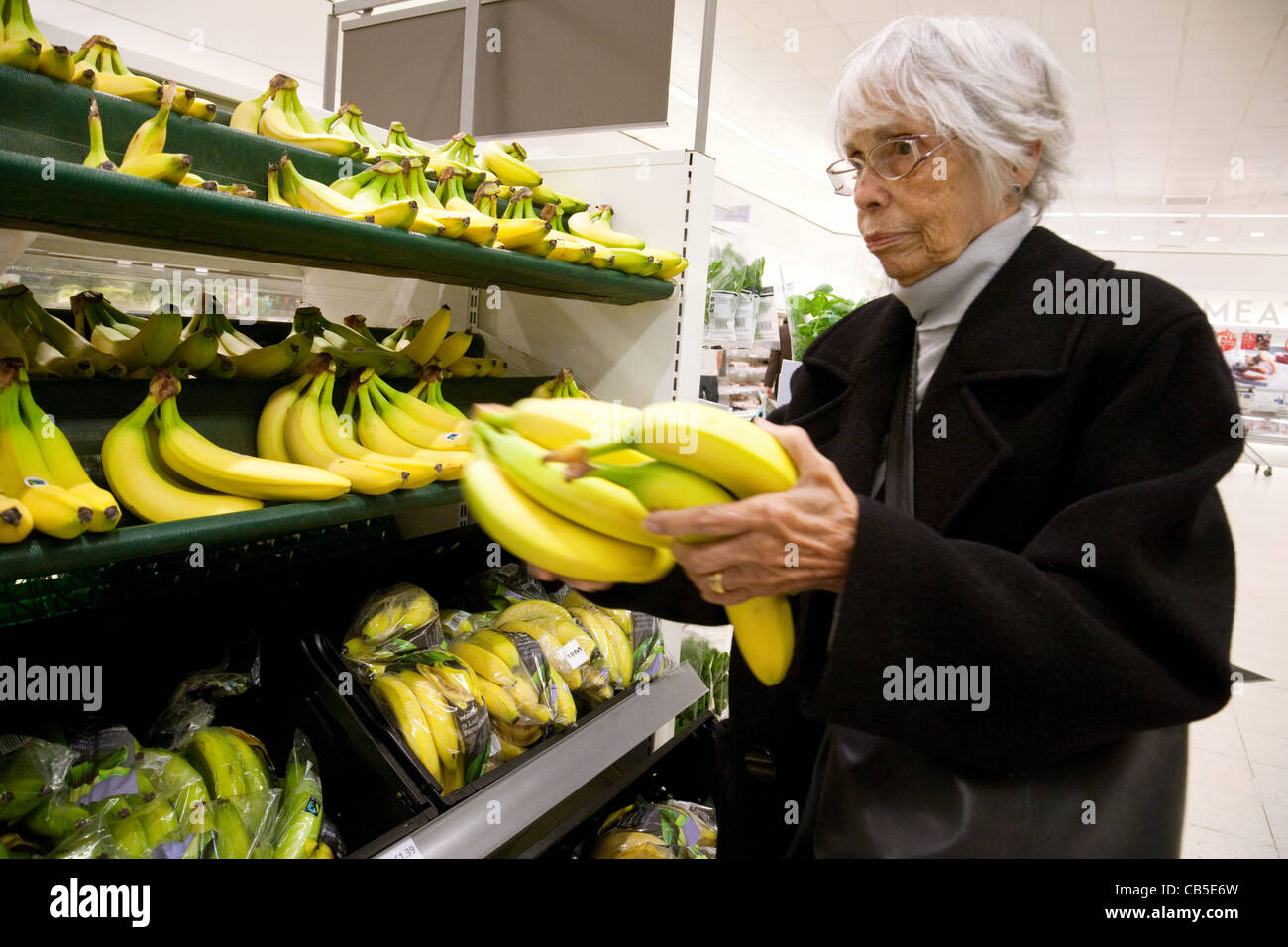 An elderly woman buying bananas fruit in Waitrose supermarket ...