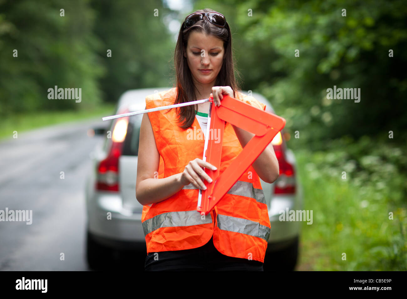 Young female driver wearing a high visibility vest, calling the ...