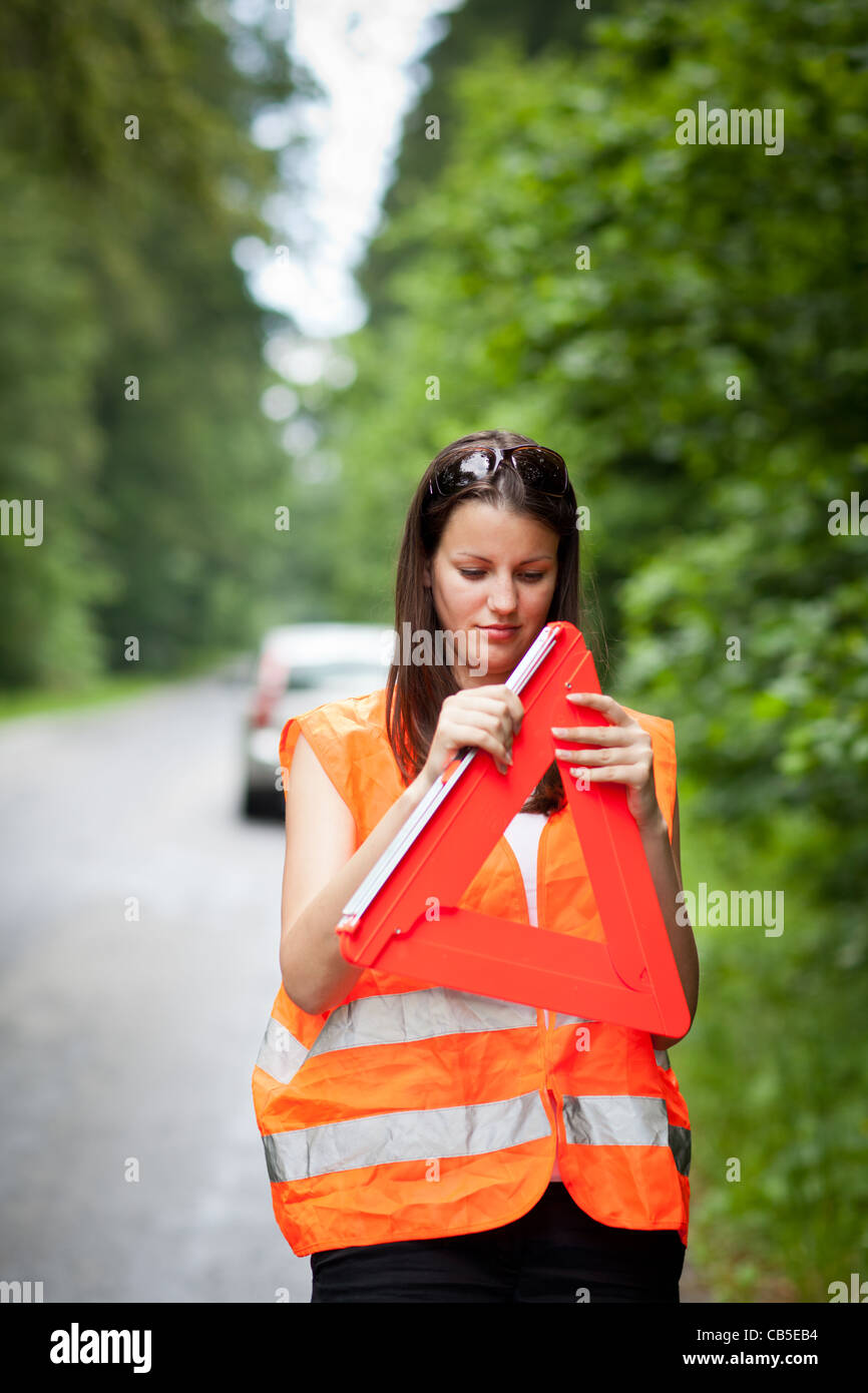 Young female driver wearing a high visibility vest, calling the ...
