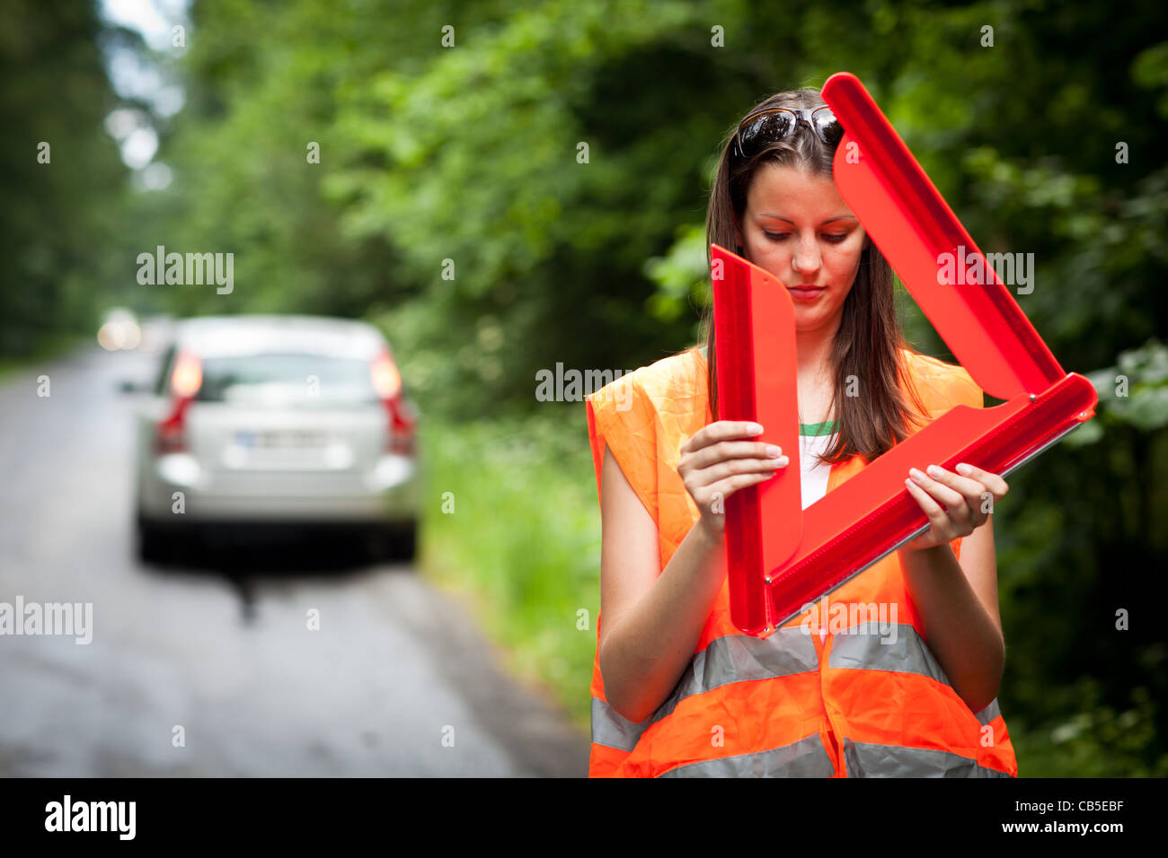 Young female driver wearing a high visibility vest, calling the ...