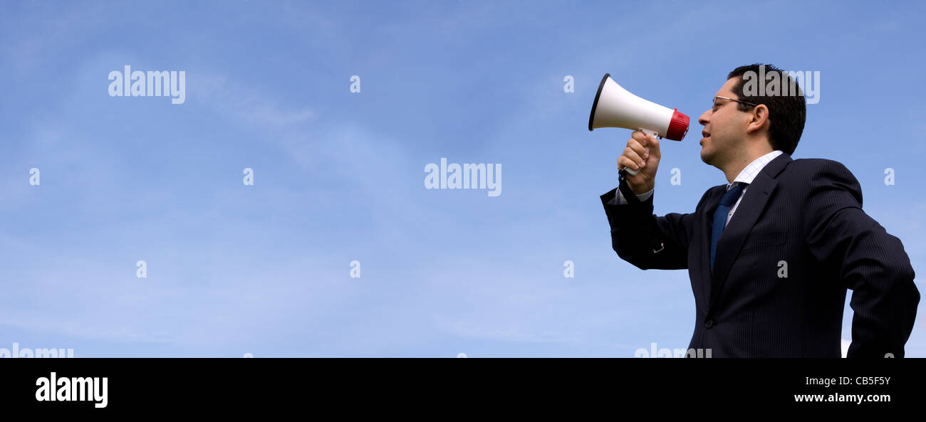 Businessman speaking with a megaphone with the blue sky as background ...