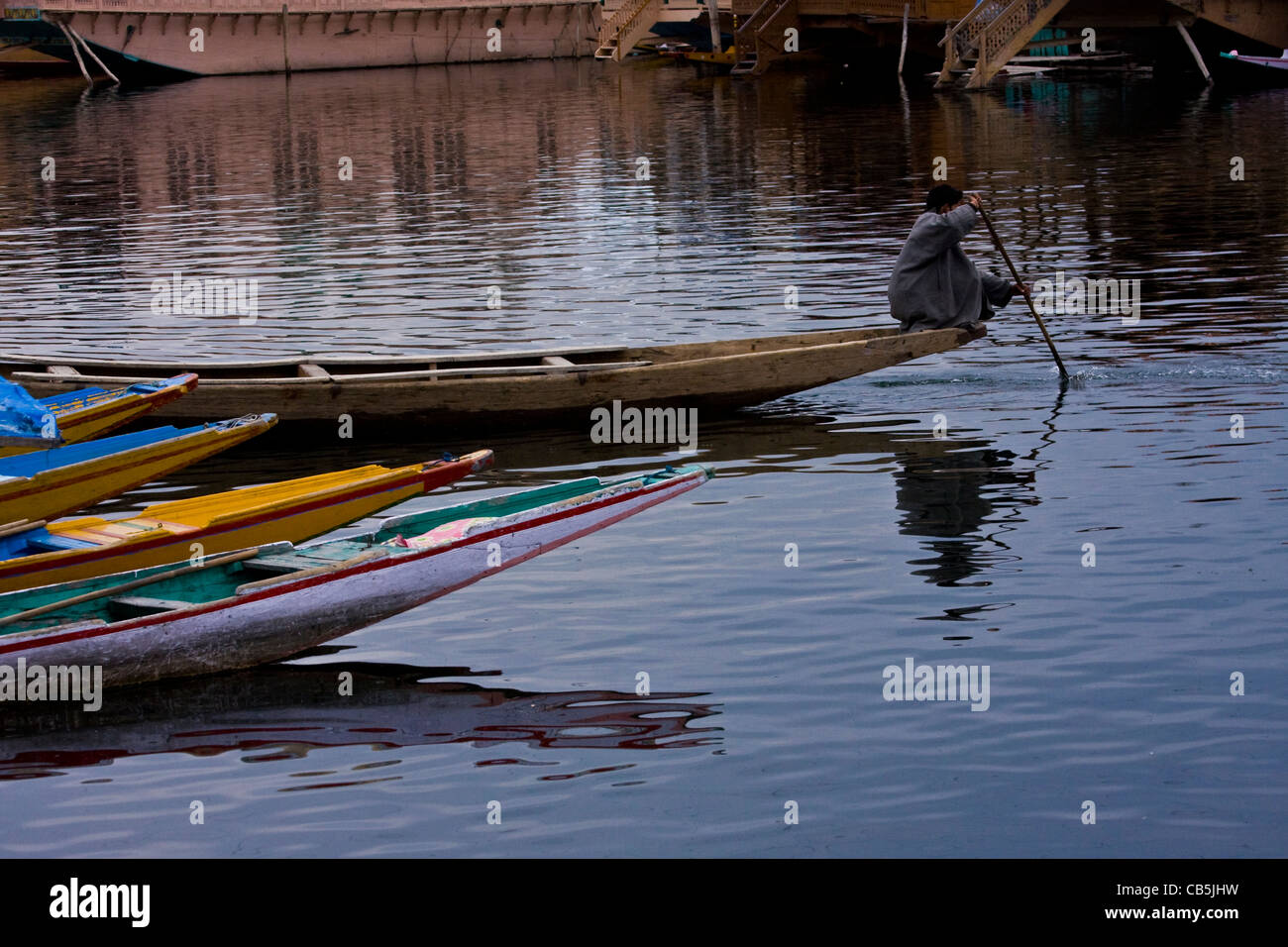 A Kashmiri man rowing a country boat/canoe/boat/shikara in the Dal Lake ...