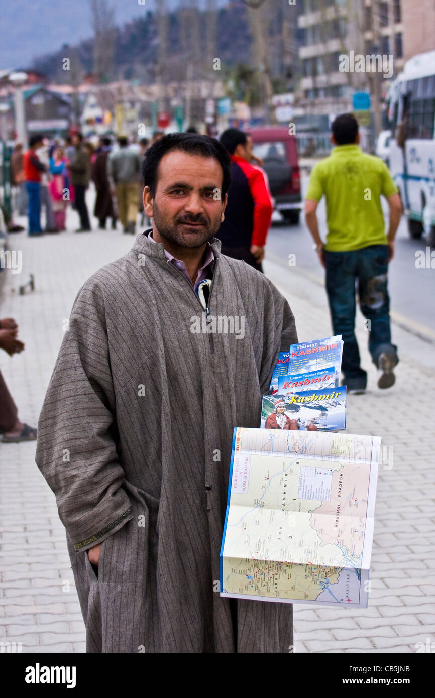A Kashmiri man in traditional cloth selling things on the footpath ...