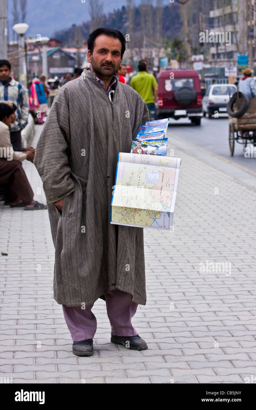A Kashmiri man in traditional cloth selling things on the footpath ...