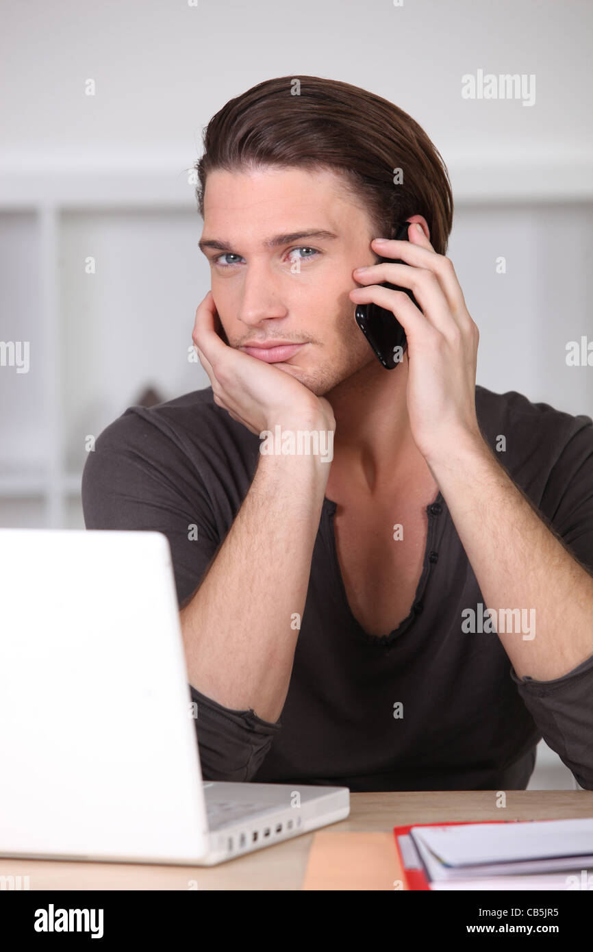handsome blue-eyed young man phoning and computer Stock Photo - Alamy