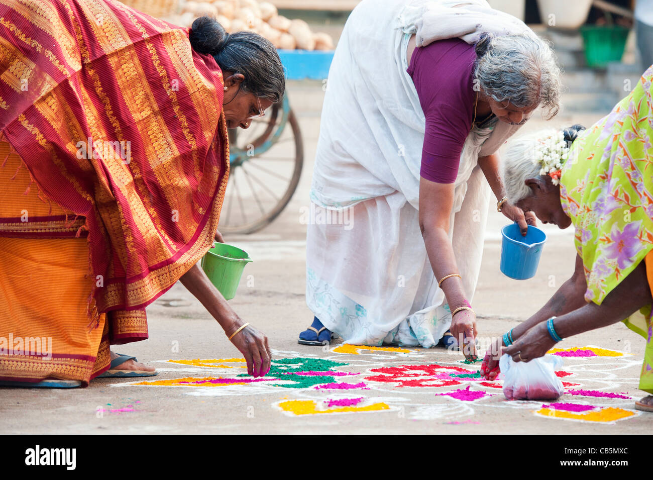 India women making a Rangoli festival design in an Indian street ...