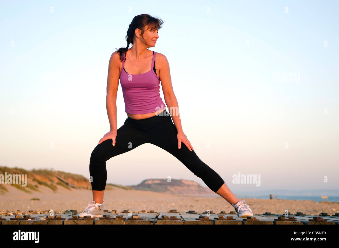 A woman stretching on the beach Stock Photo - Alamy