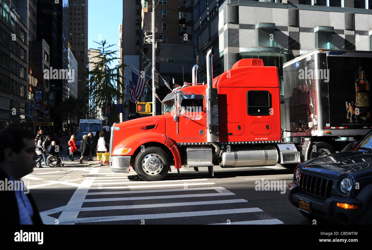 Large red truck amongst the traffic driving through centre of Manhattan ...