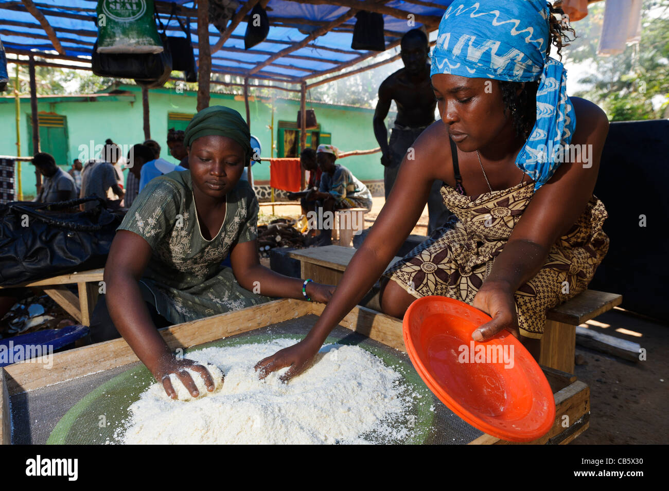 Women working in a small factory that produces garri from cassava root ...