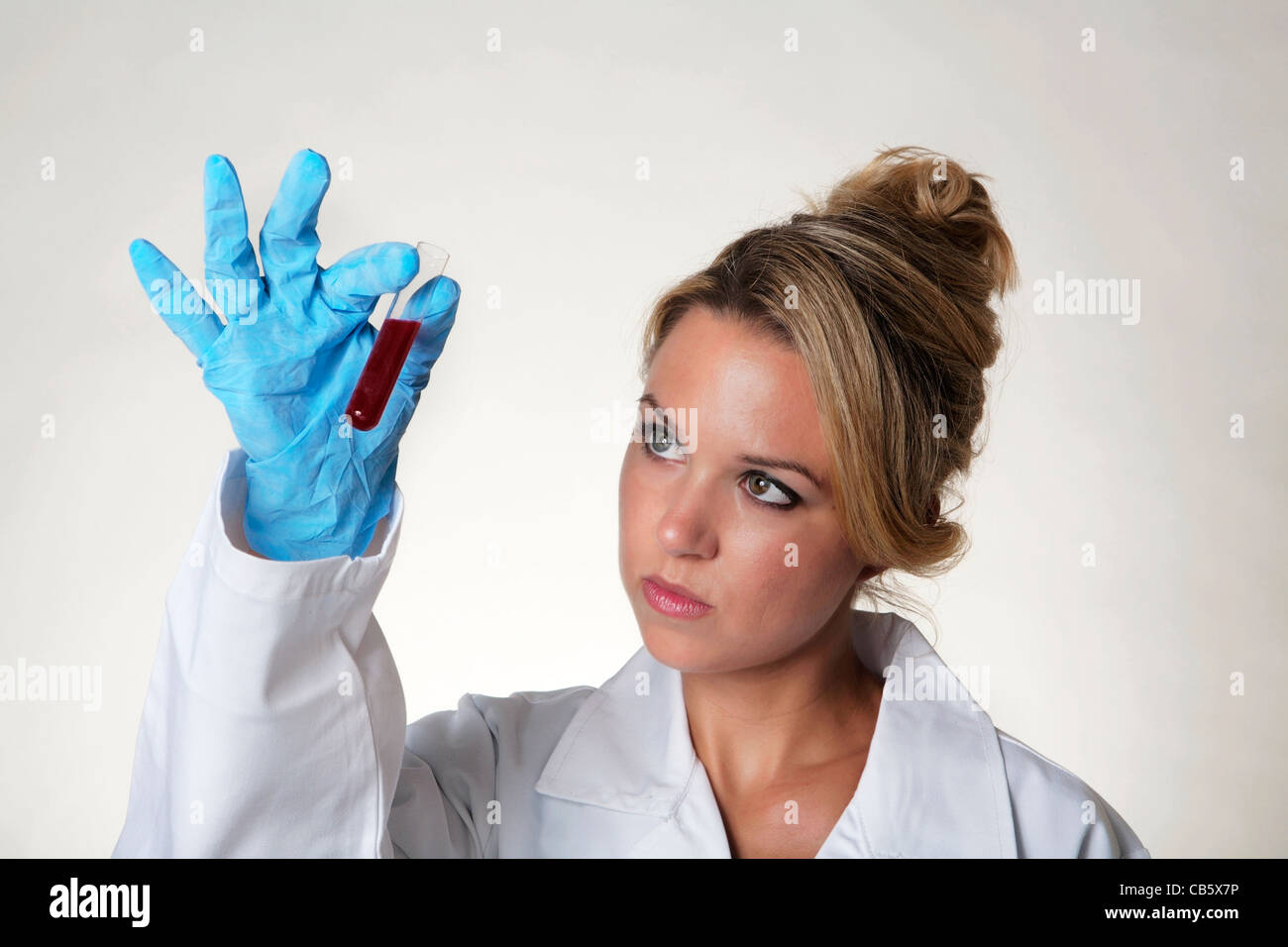 woman holding up a test tube looking at whats happen inside Stock Photo ...