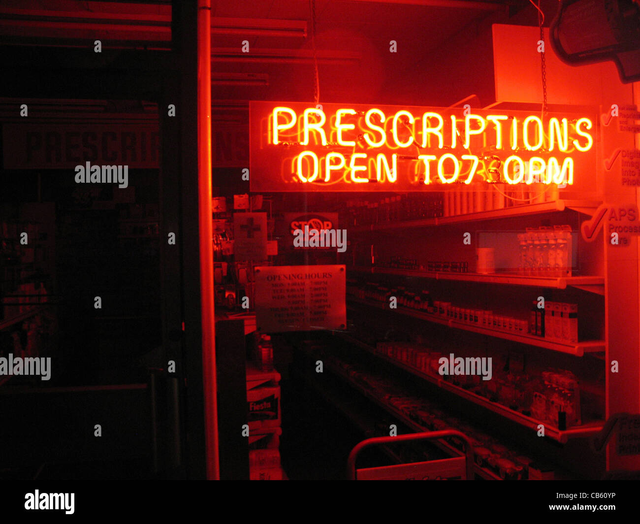 Chemist shop window at night with a glowing red neon sign saying ...