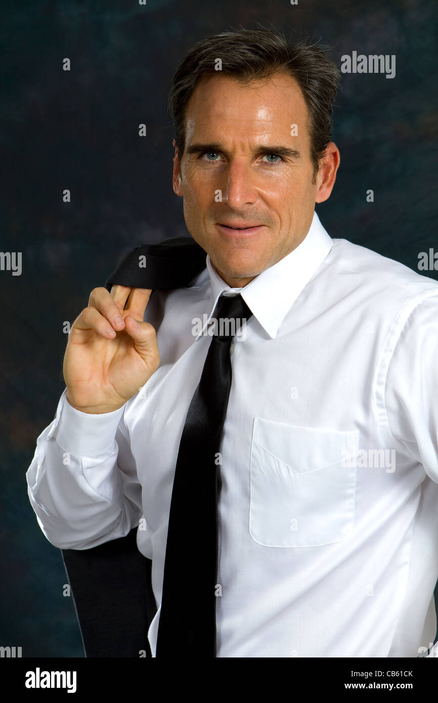 Confident businessman wearing white shirt and tie has his coat draped ...