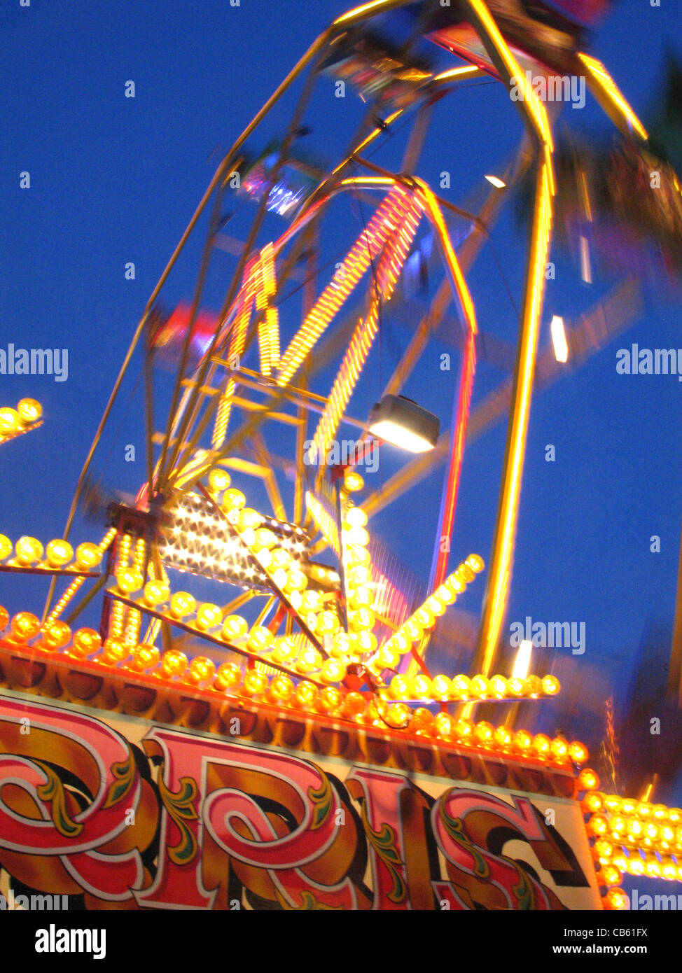 Traditional ferris wheel spinning against an early evening summer blue ...