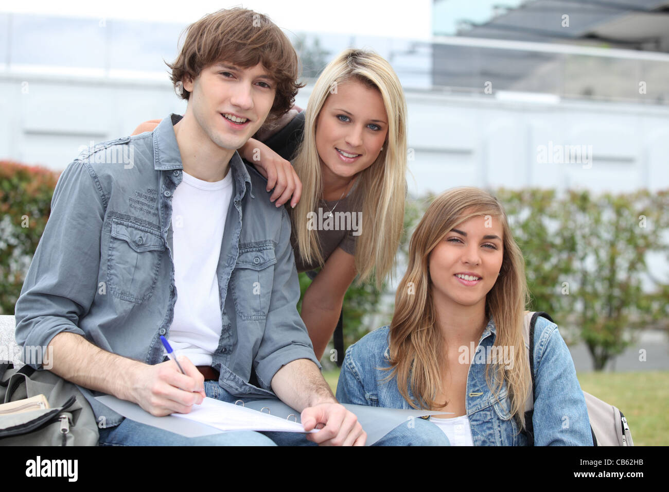 Three young students smiling at us on a campus Stock Photo - Alamy