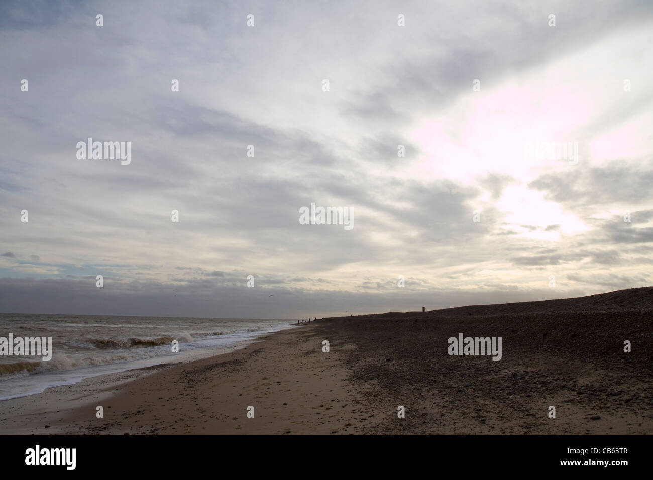 A family in the far distance stroll along the wild and windswept beach ...