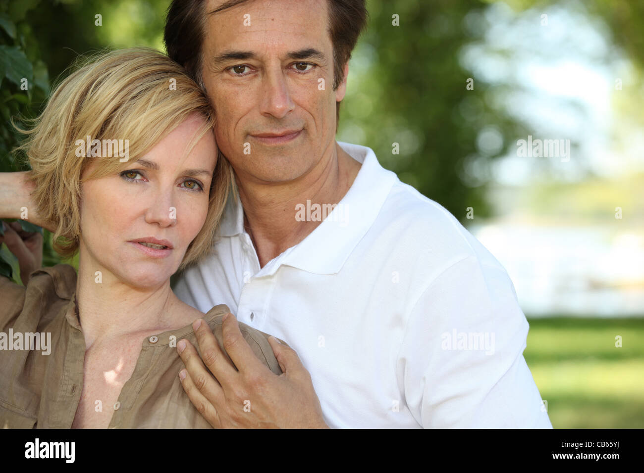 Sultry couple stood by tree in park Stock Photo - Alamy
