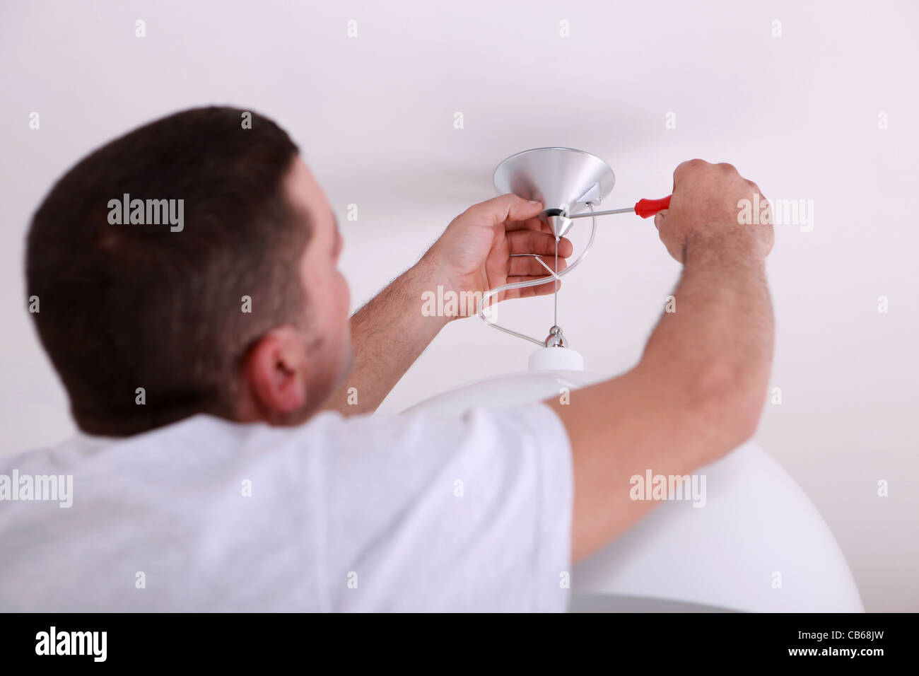 Man repairing ceiling light with screwdriver Stock Photo - Alamy