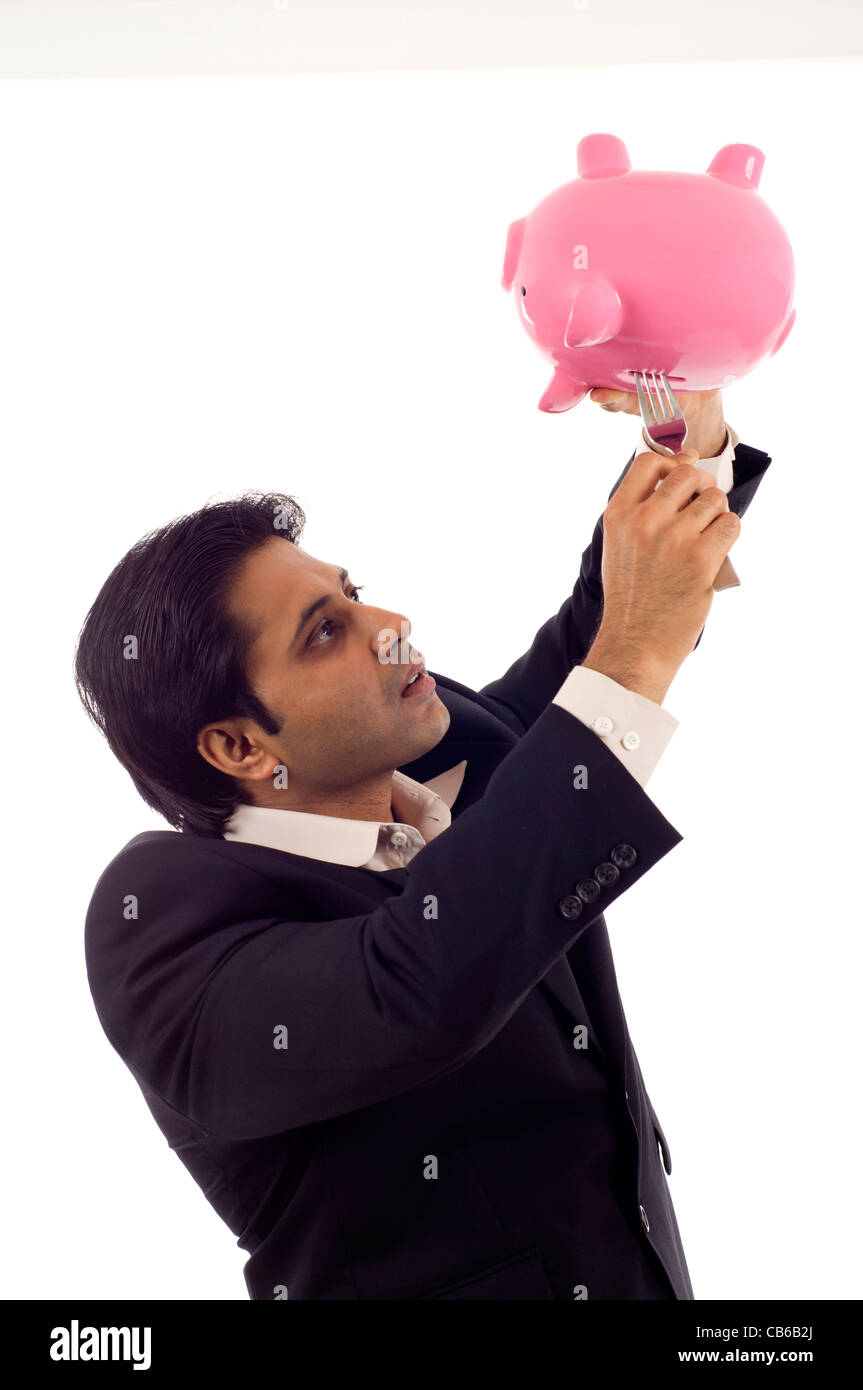 Desperate Indian businessman trying to take money out of a piggybank ...