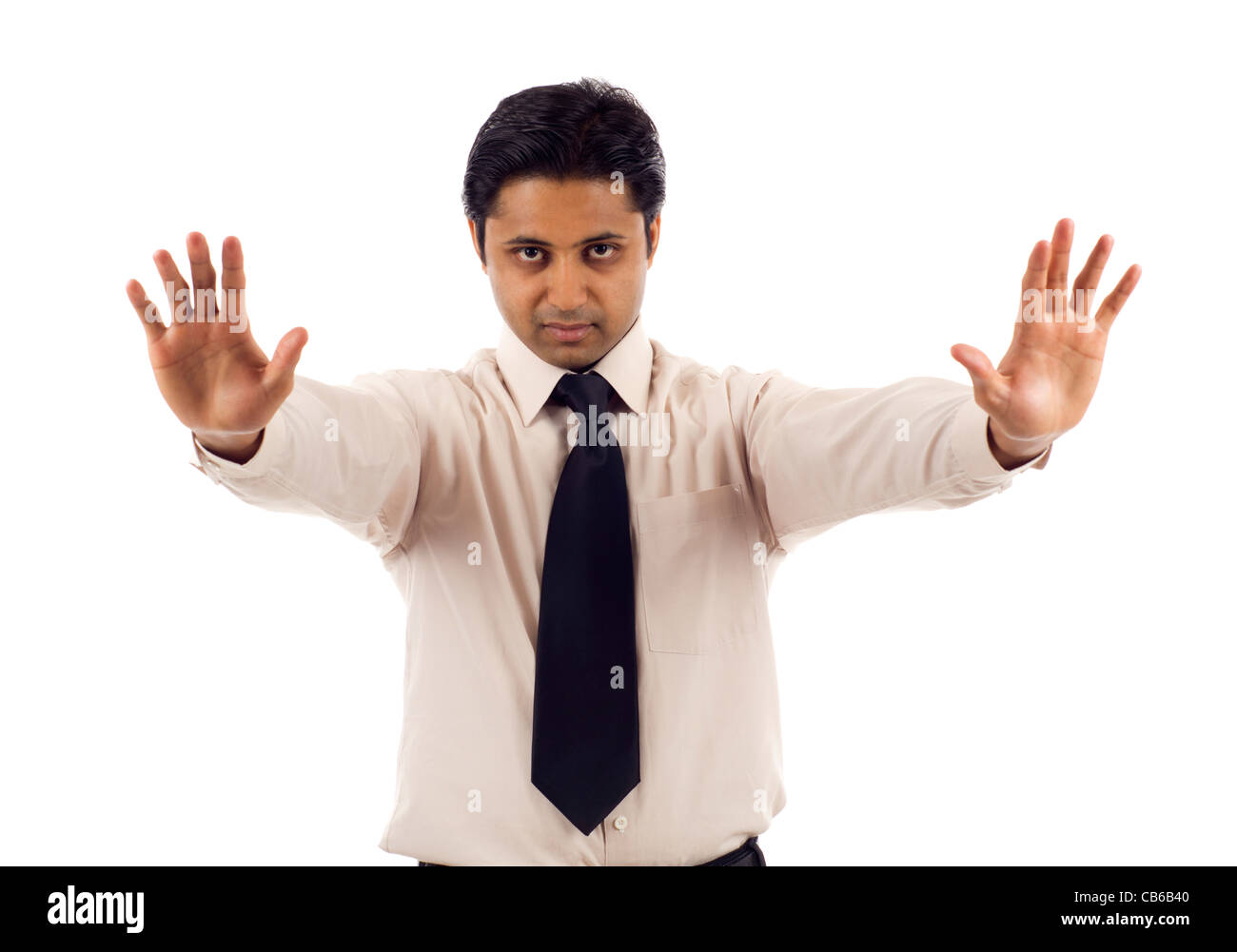 Serious looking Indian businessman with his hands raised in signal to ...