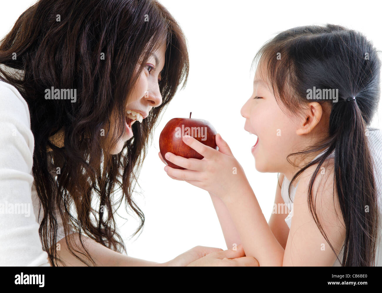 Mother and daughter sharing an apple on white background Stock Photo ...