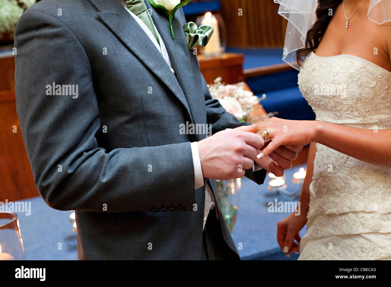 Groom is placing wedding ring on bride's ring finger during wedding ...