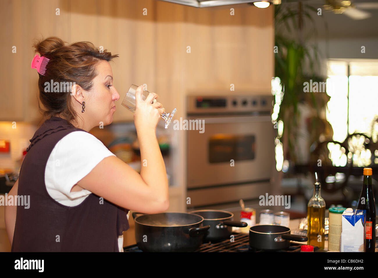 Housewife drinking wine while cooking in her kitchen Stock Photo - Alamy
