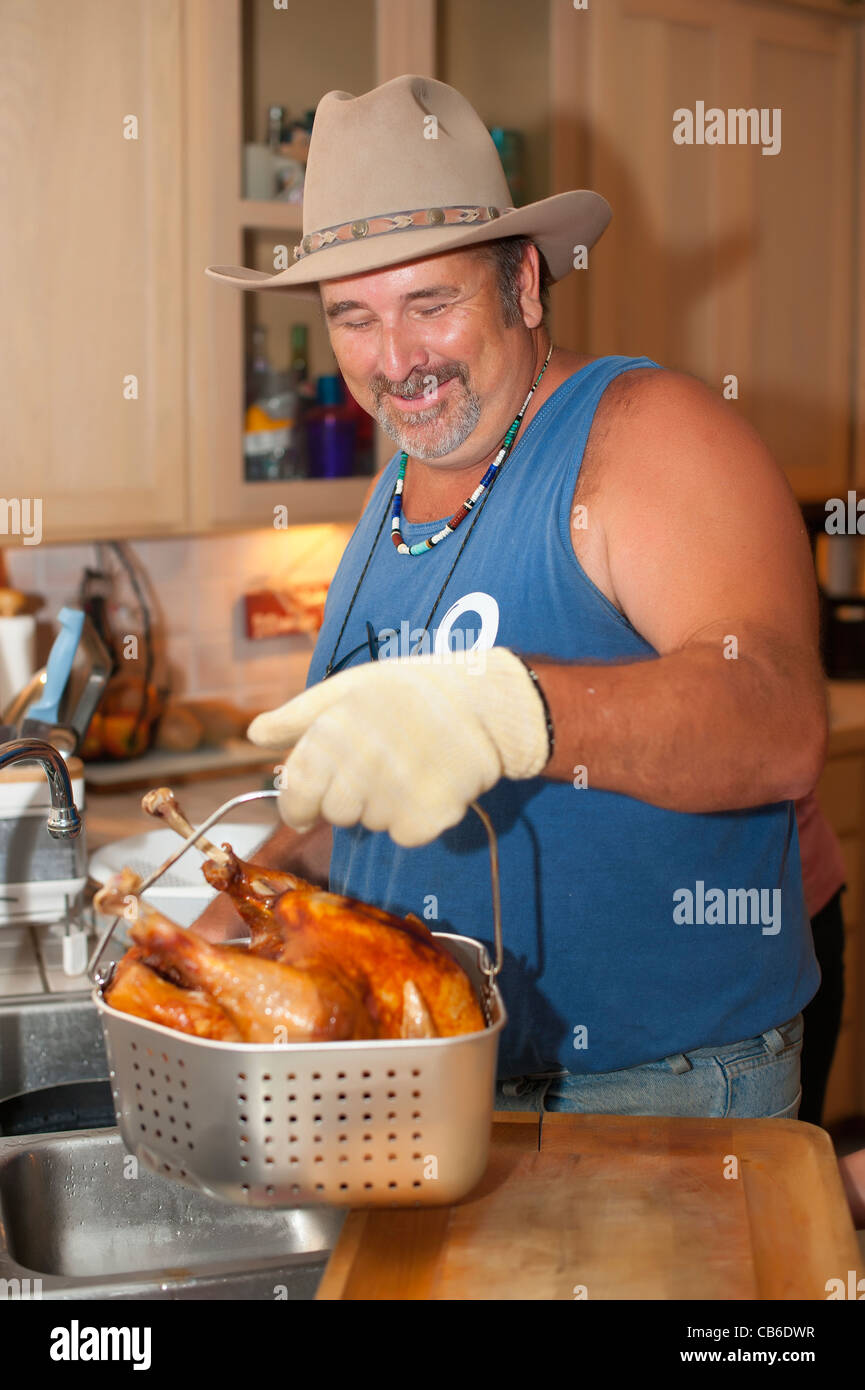 Man of the house proudly frying turkey roast Stock Photo - Alamy
