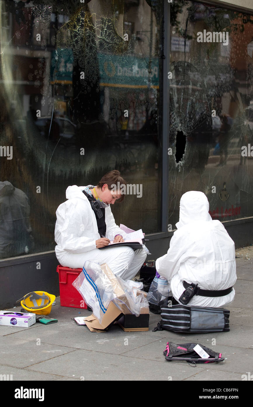 Police forensics search a burnt out Foot Locker sports wear store ...