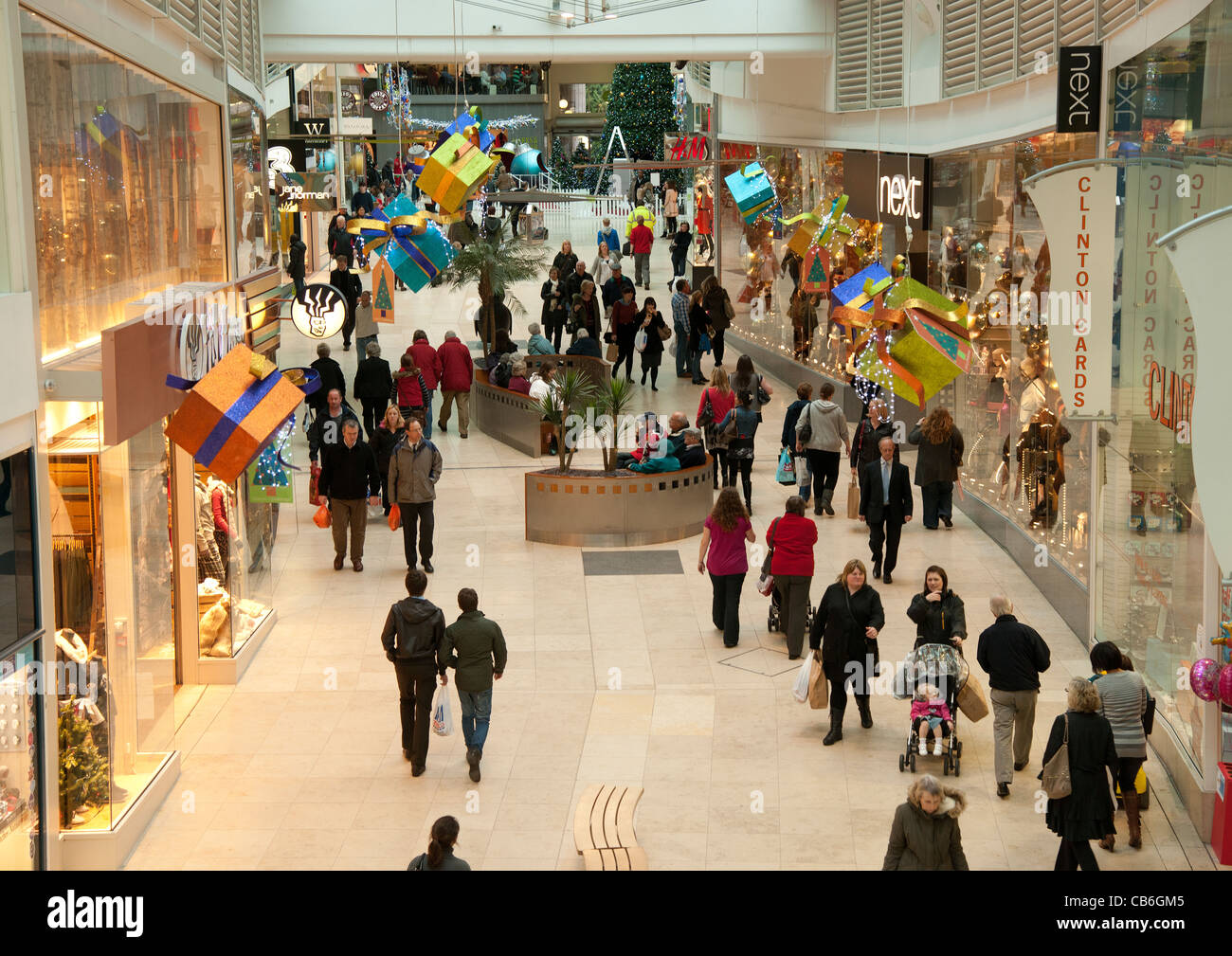 Shoppers stroll through a busy indoor shopping mall decorated for ...