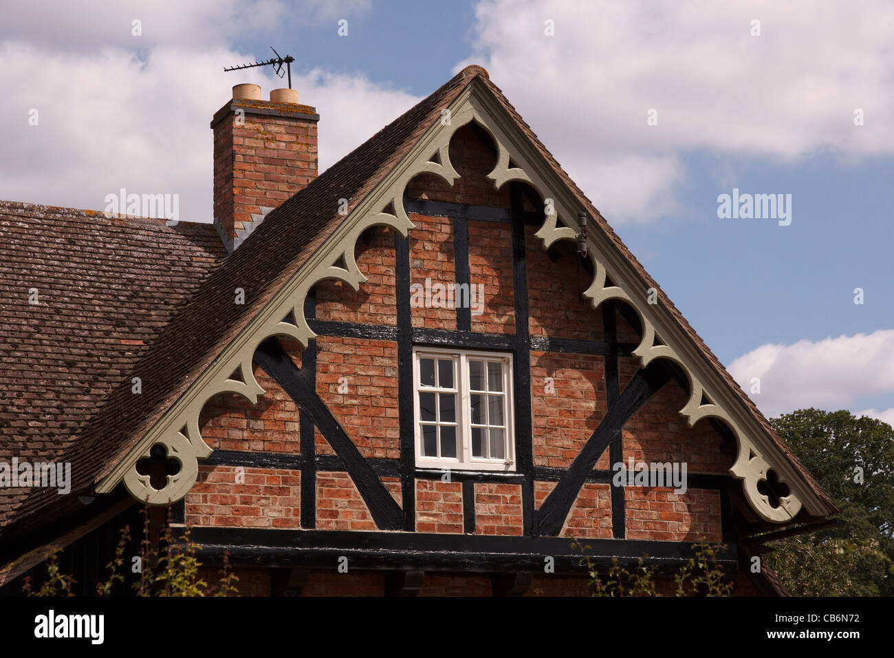 Ornate green painted eaves on gable end of old brick and oak beam ...