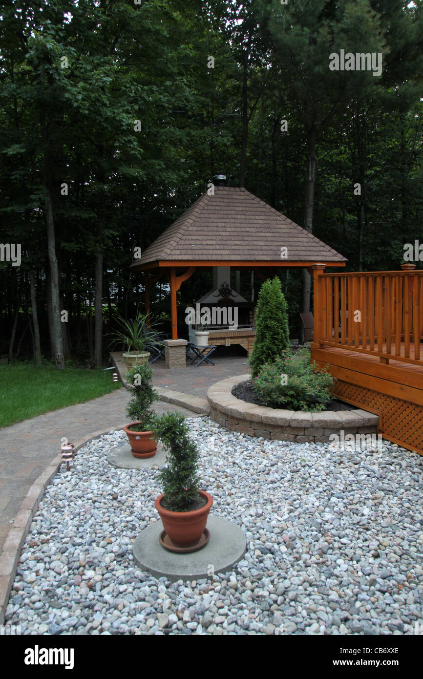 Garden with tall trees stones grass and barbecue Stock Photo - Alamy