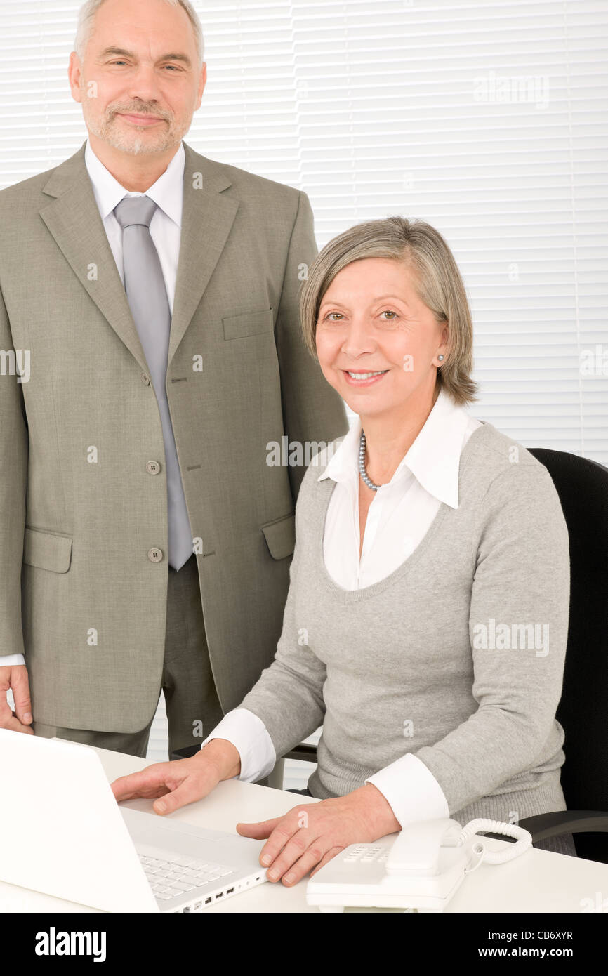 Professional senior businesswoman behind computer with male colleague ...