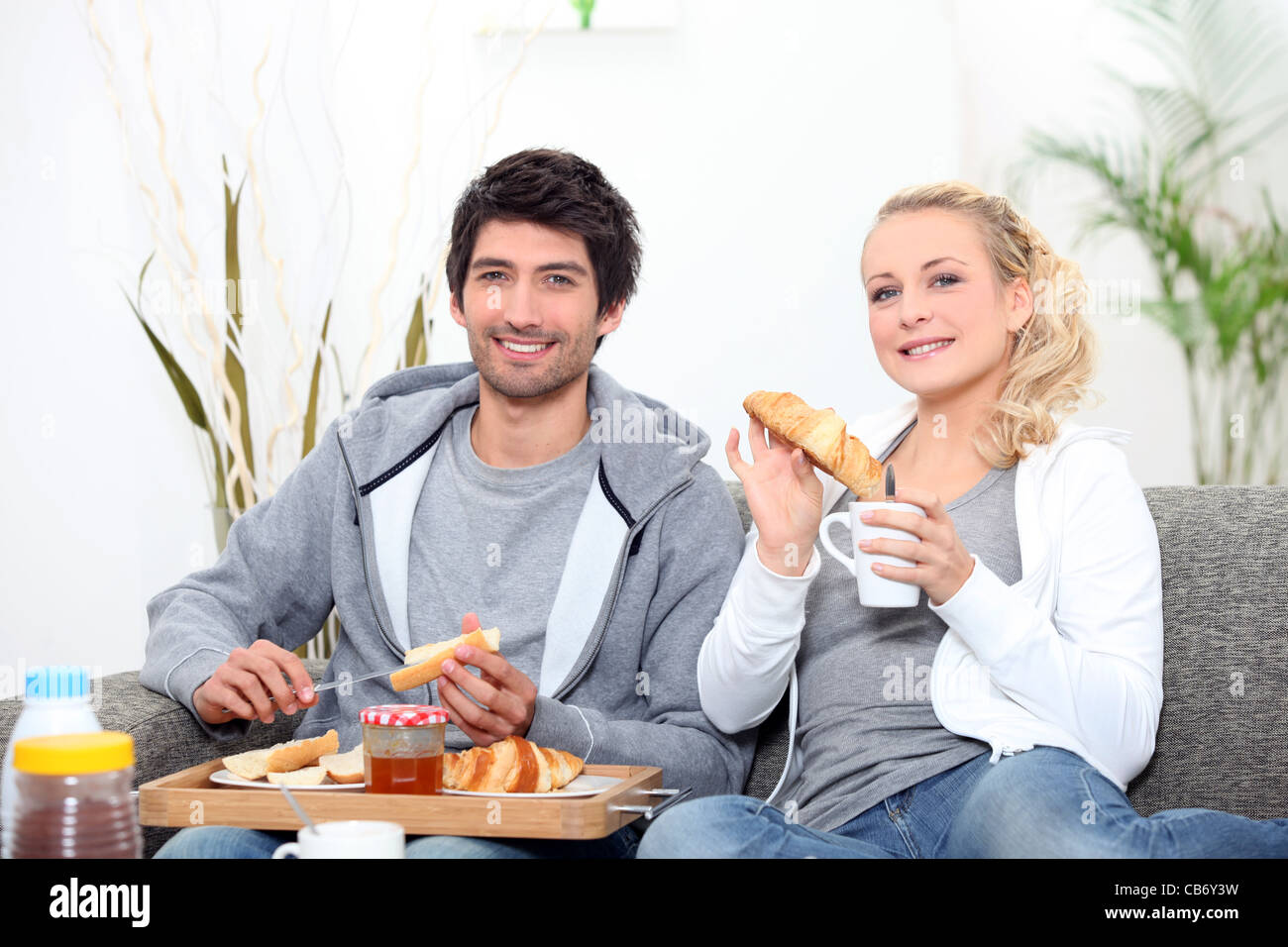 Young couple sharing breakfast in the lounge Stock Photo - Alamy