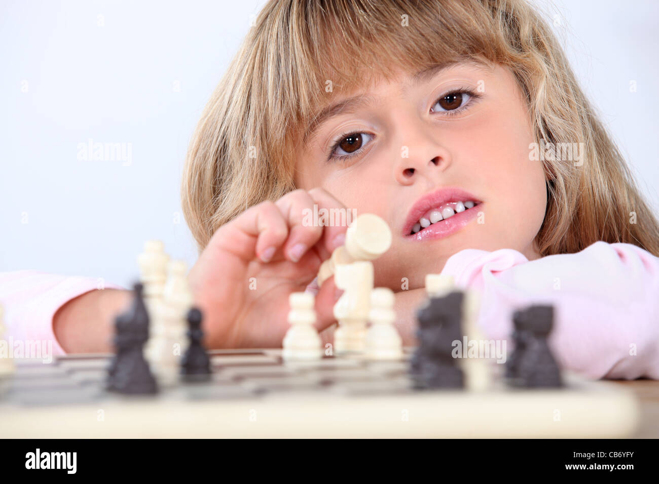 Cute blond girl playing chess Stock Photo - Alamy