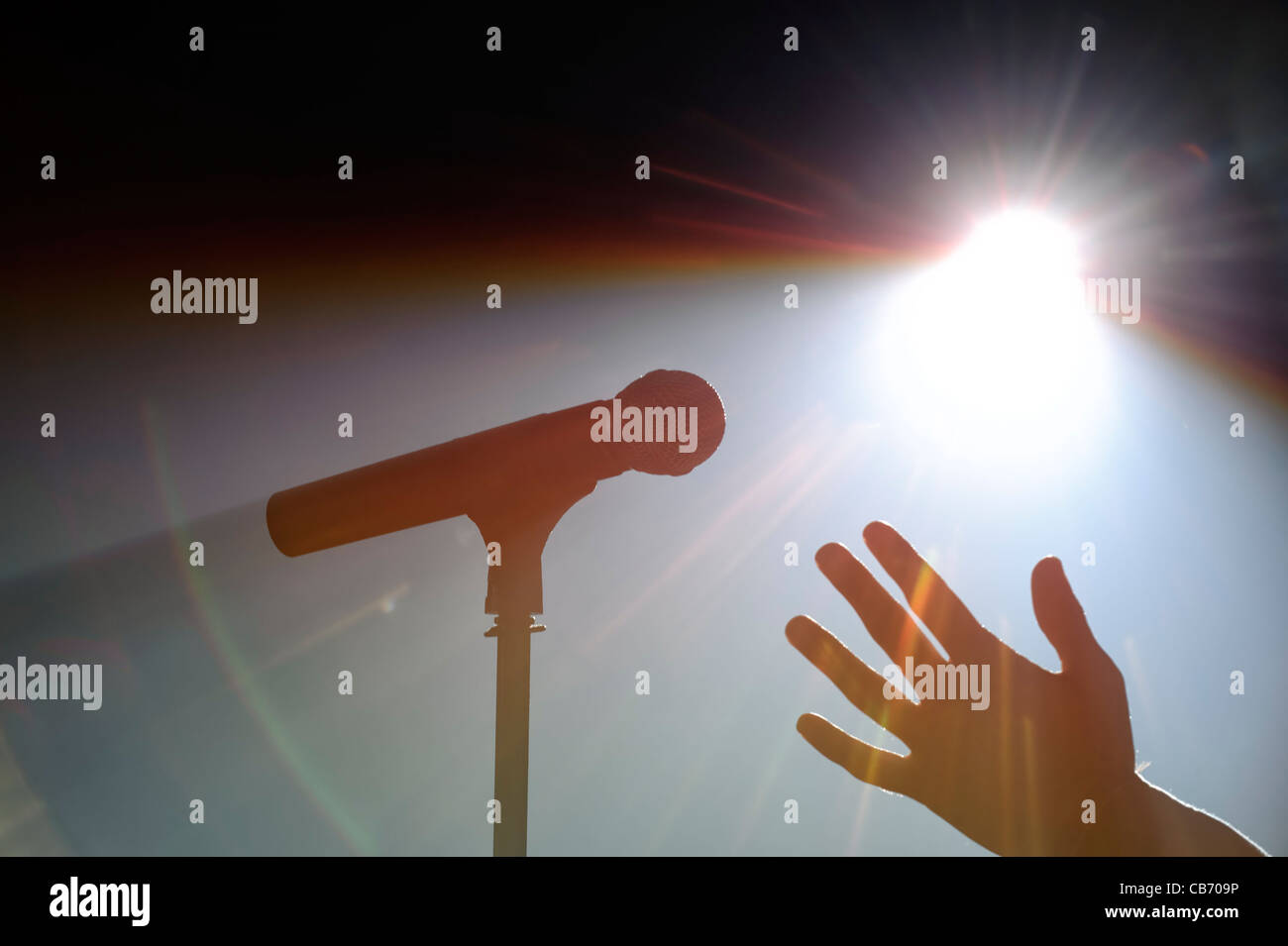 Spot lit microphone on stand and hand on an stage Stock Photo - Alamy