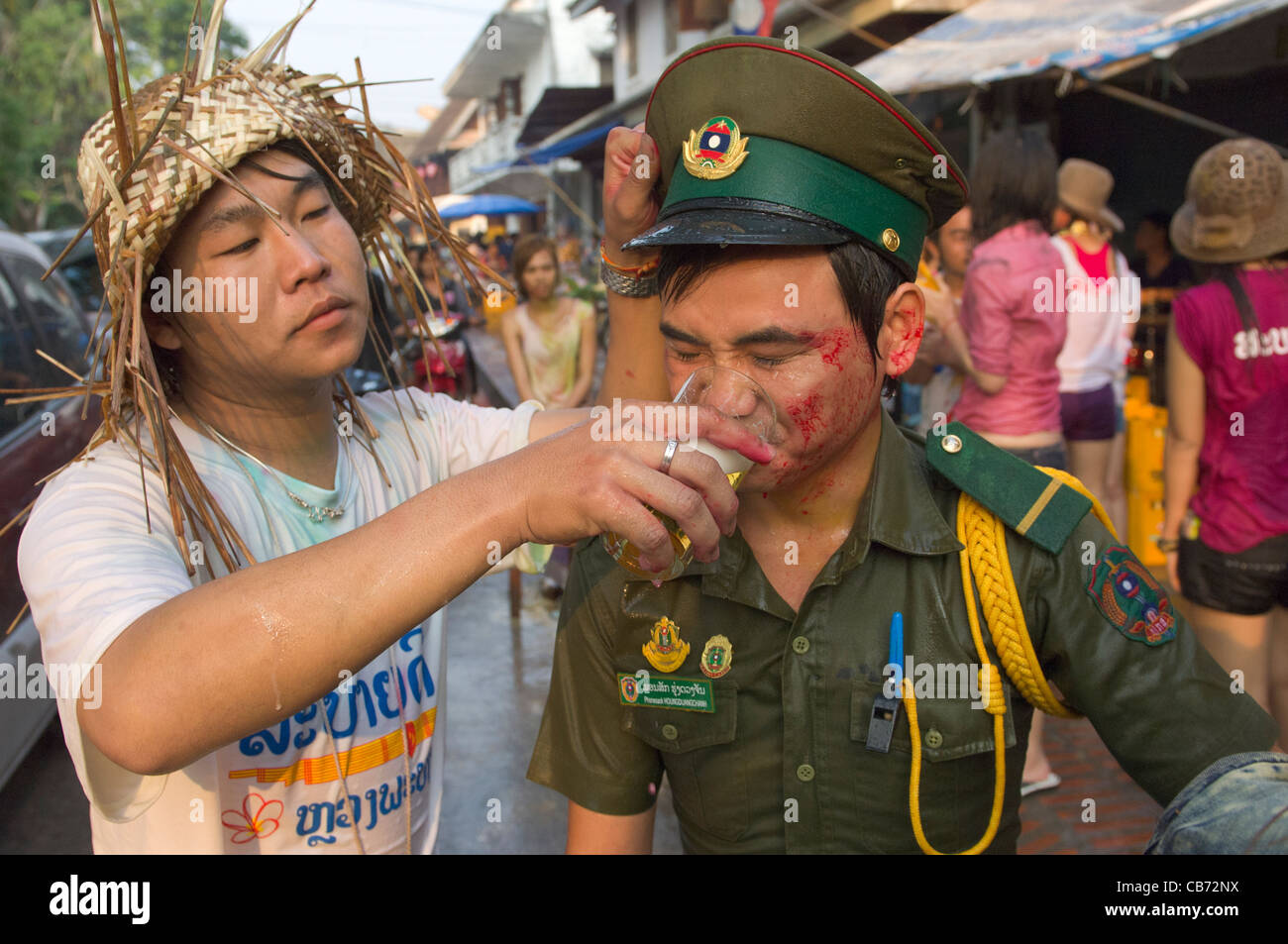 Lao Policeman being forced to drink beer during a water-fight to ...