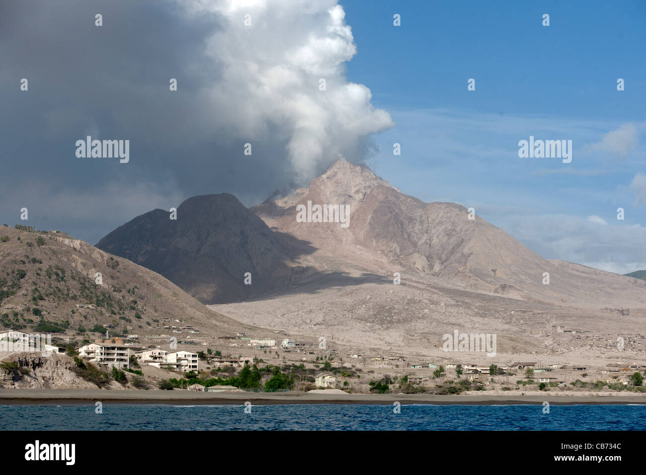 Smoking Soufriere Hills Volcano towering above the ruined former ...