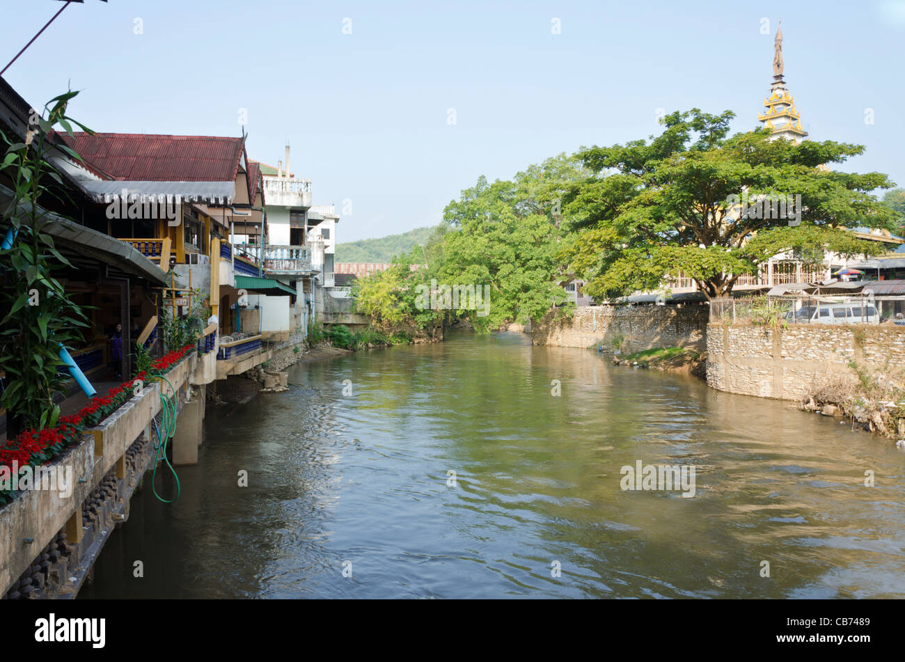 Mae Nam Sai river has Maesai Thailand on left with red flower lined ...