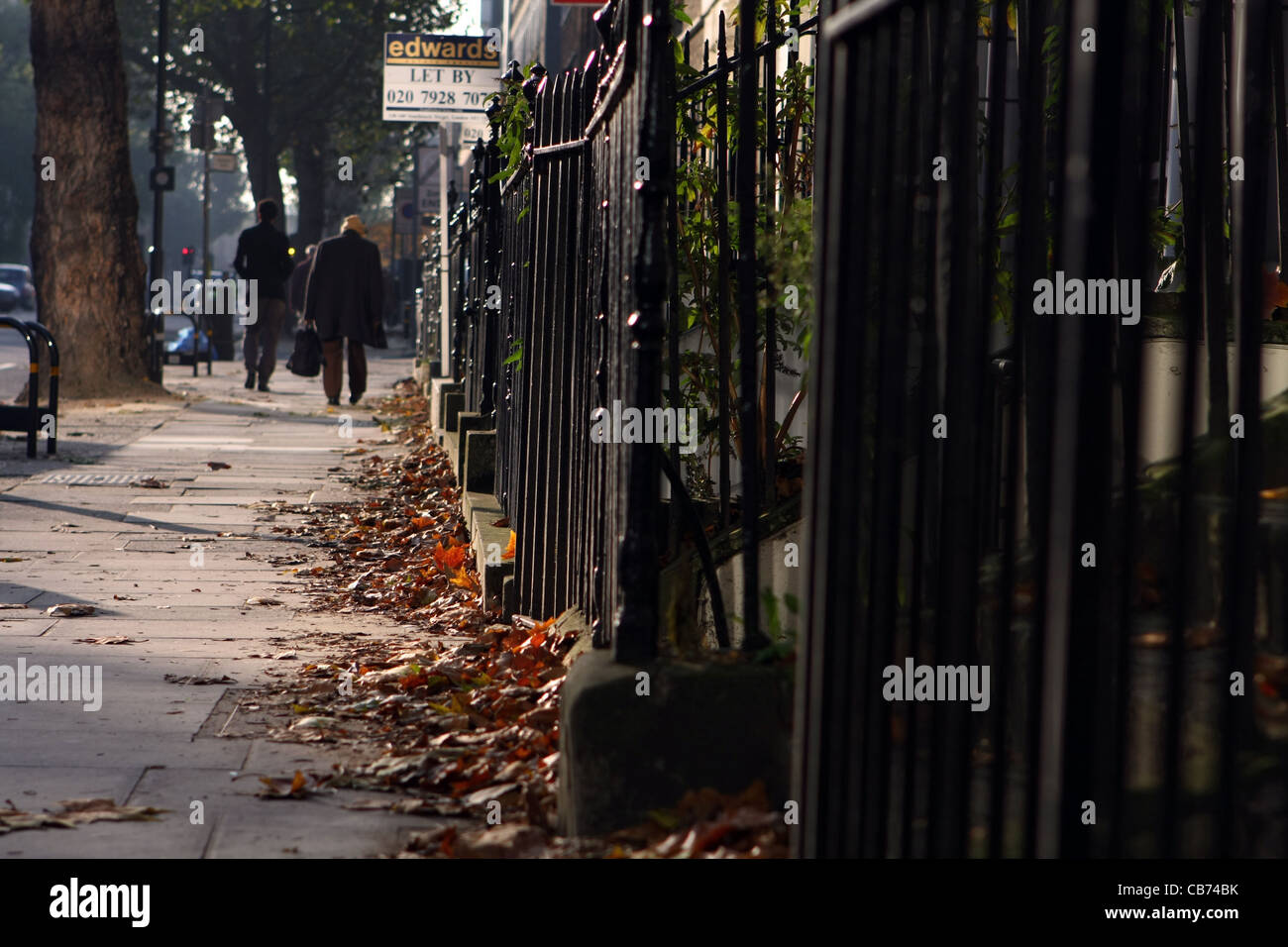 a low view along a street in London with railings on the right and ...