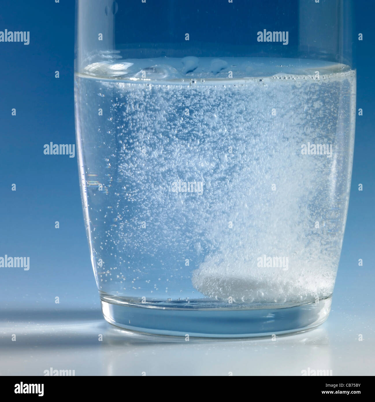 dissolving fizzy tablet floating in a glass of water. Studio ...