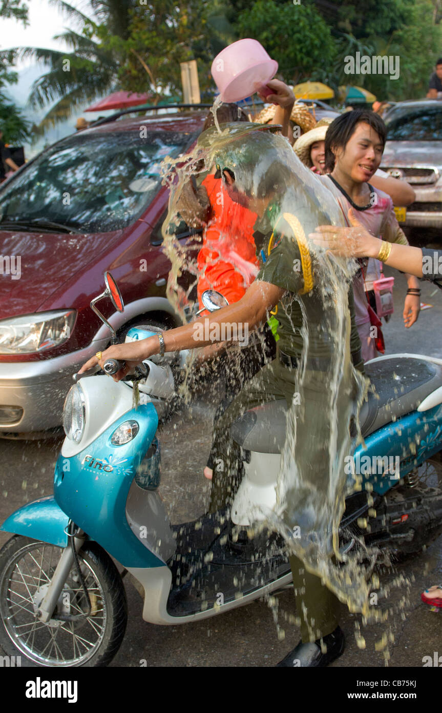 Lao Policeman on a moped getting water poured, during a water-fight to ...