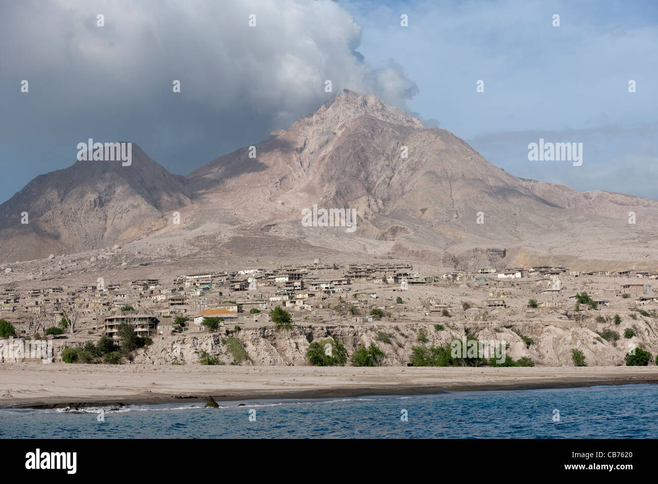 Smoking Soufriere Hills Volcano towering above the ruined former ...
