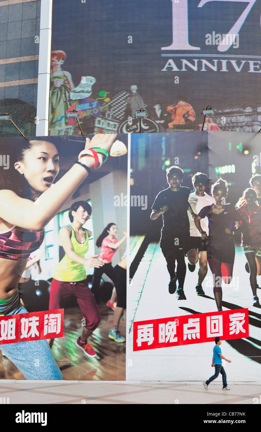 Young chinese man walking past giant neon advertising signs Wangfujing ...