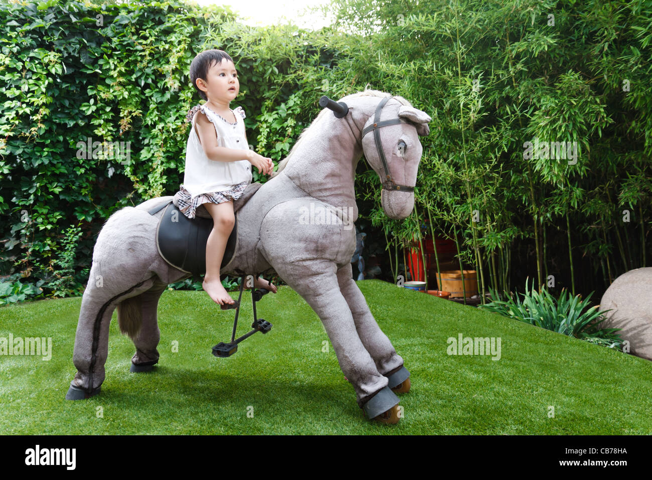 Girl riding toy horse Stock Photo - Alamy