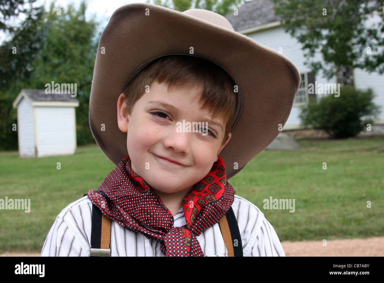 An adorable cowboy in front of a ranch house and outhouse Stock Photo ...