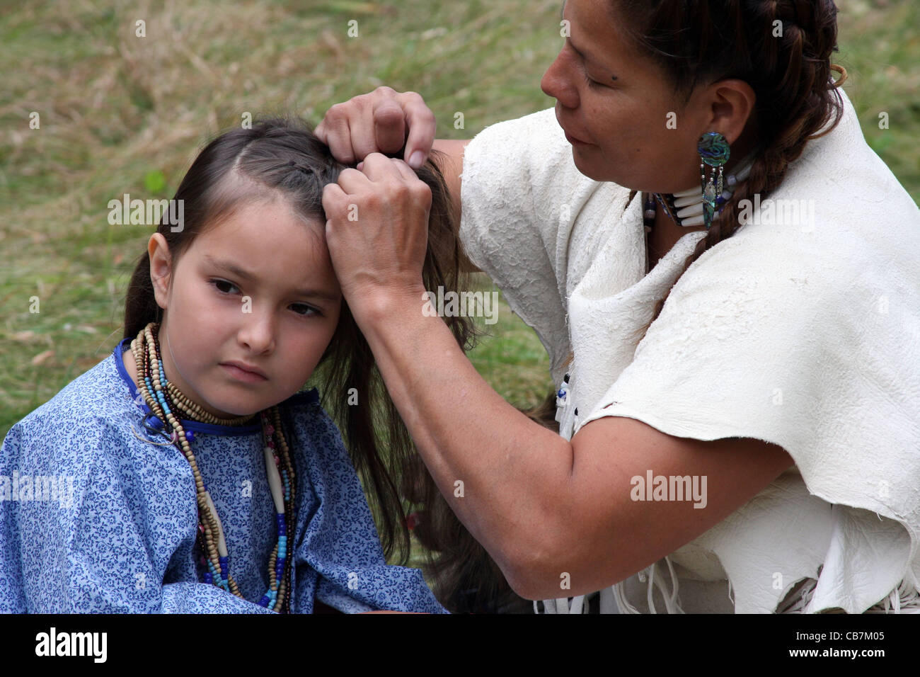 Native American Indian Lakota Sioux woman braiding the hair of a young ...