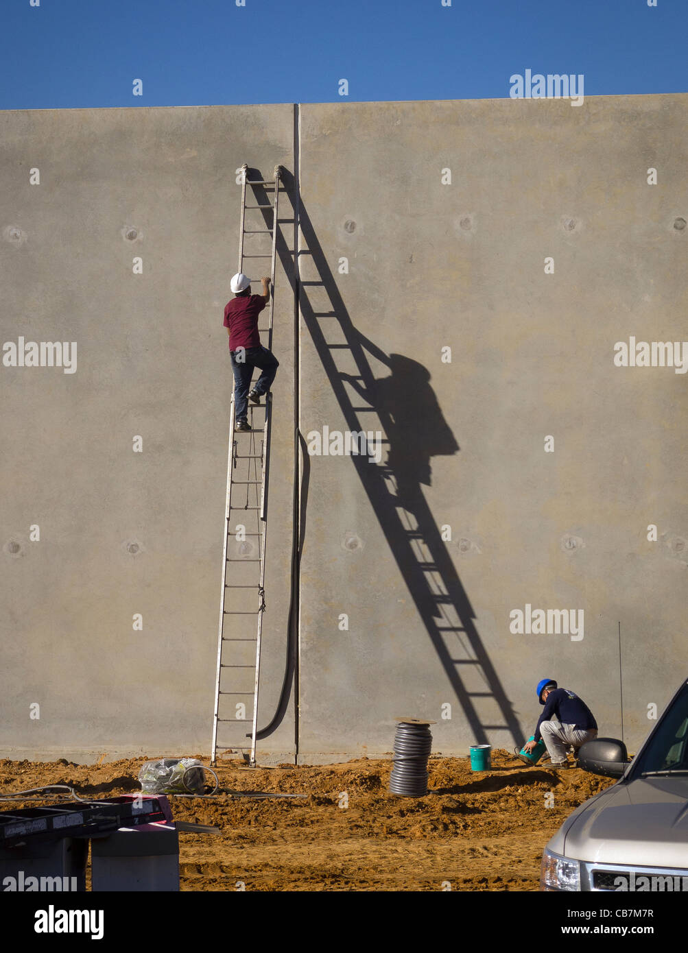 Workman on ladder casting shadow Stock Photo - Alamy